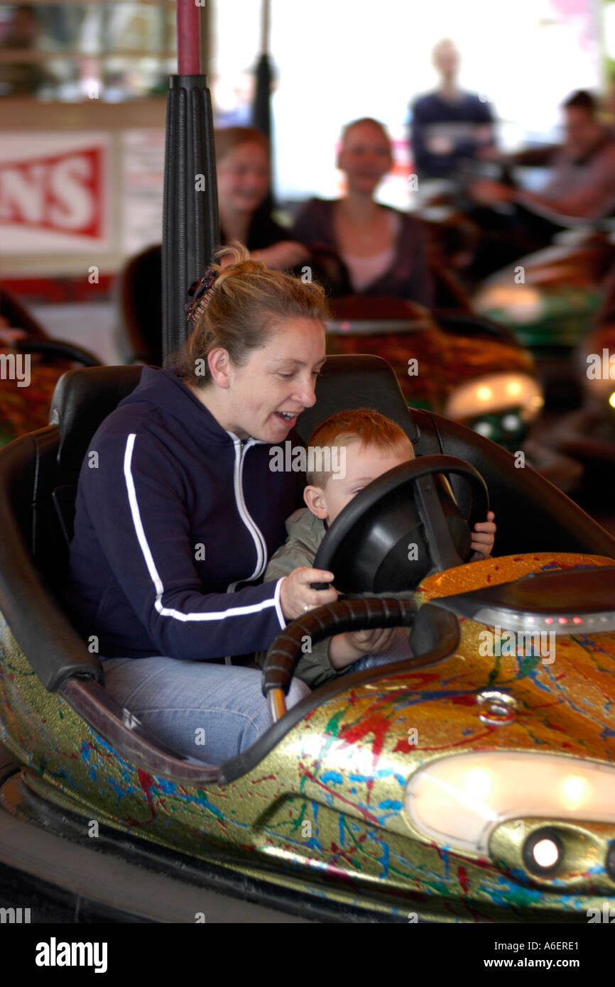 Mother and small son having fun on the dodgem cars at a fairground ...