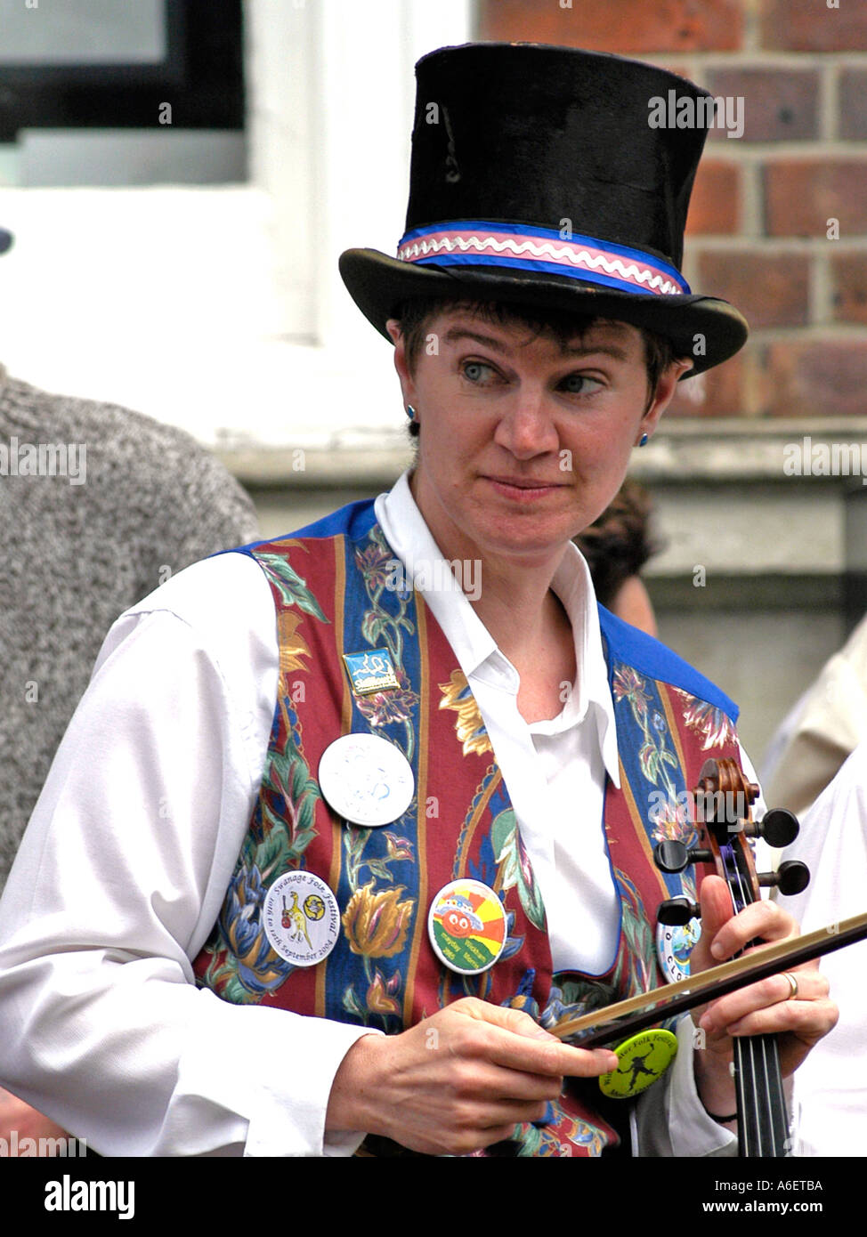 Female folk musician wearing a Tophat and colorful waistcoat performing ...