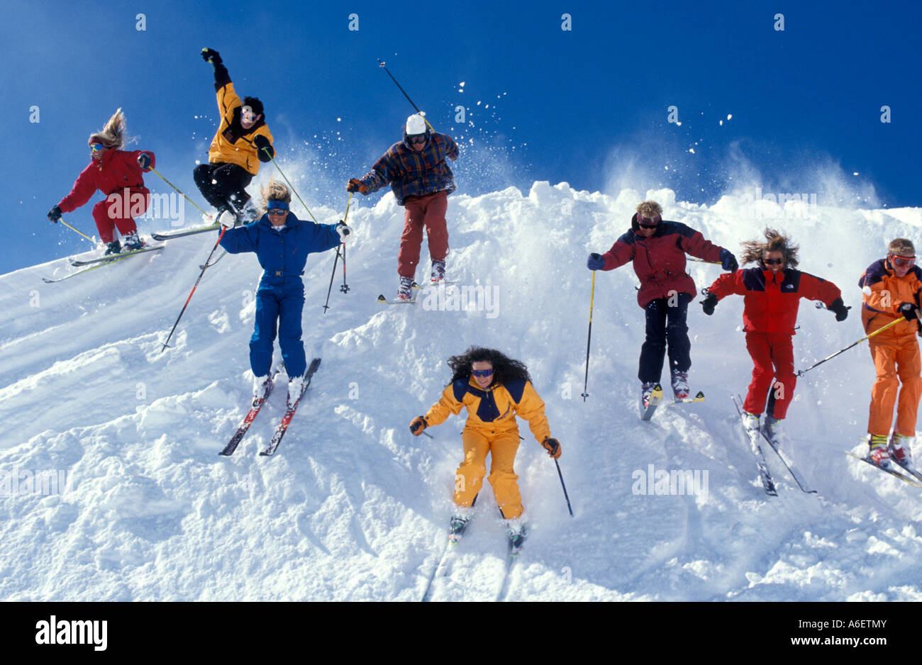 Group of young men and women skiers coming over a hill in thick snow ...