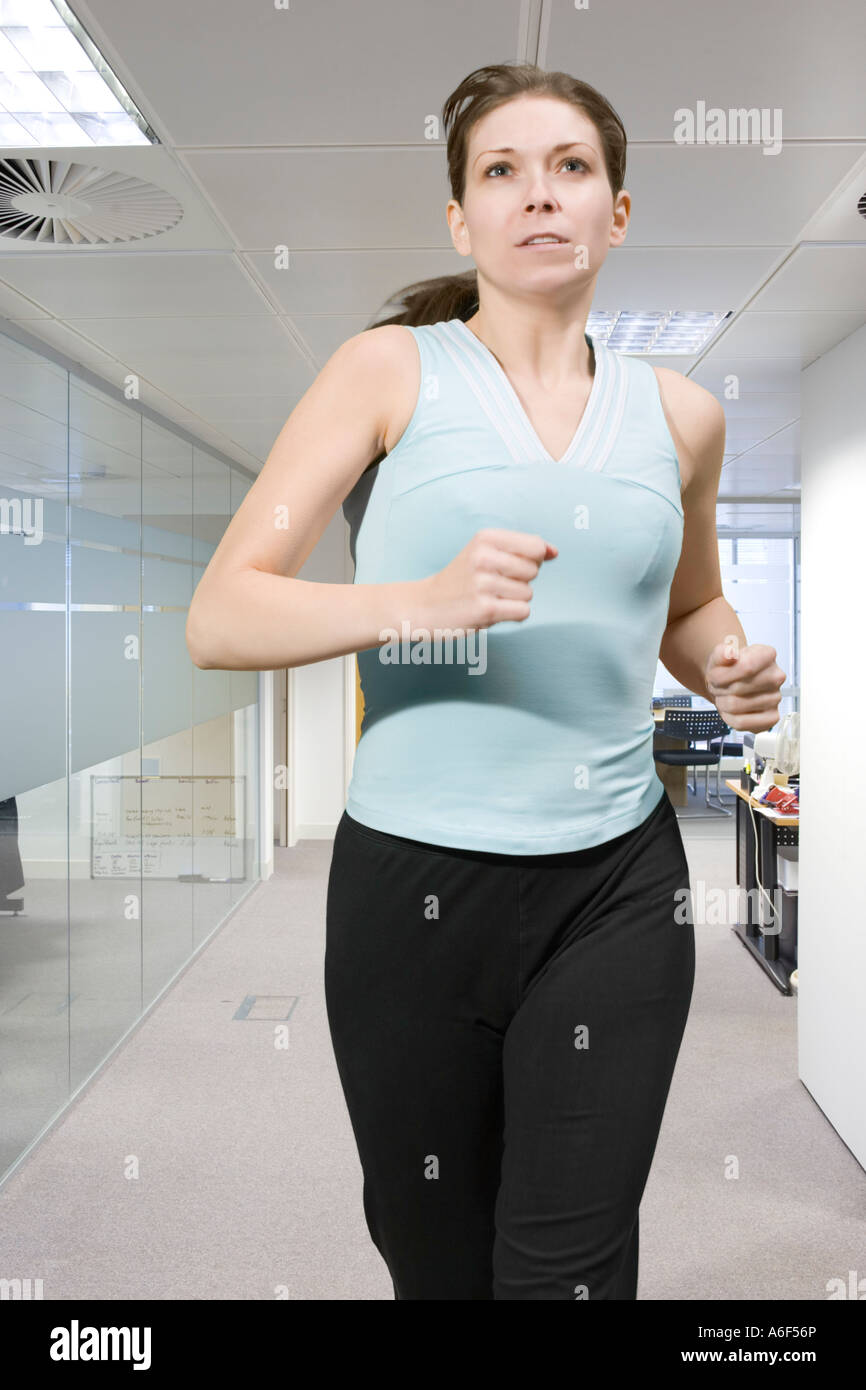 Woman in sportswear running through office Stock Photo - Alamy