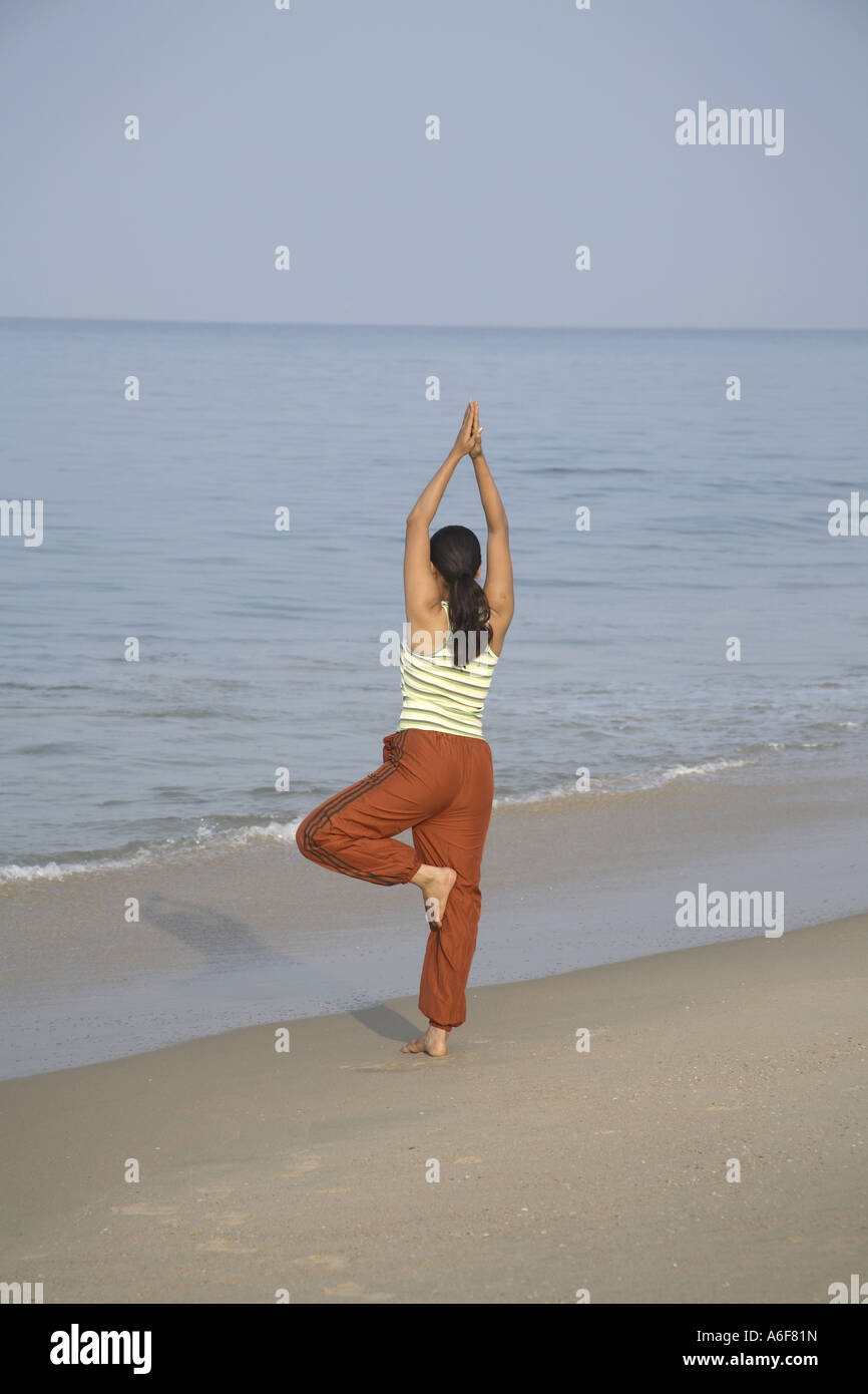 South Asian Indian young lady doing aerobics standing on one folded leg ...