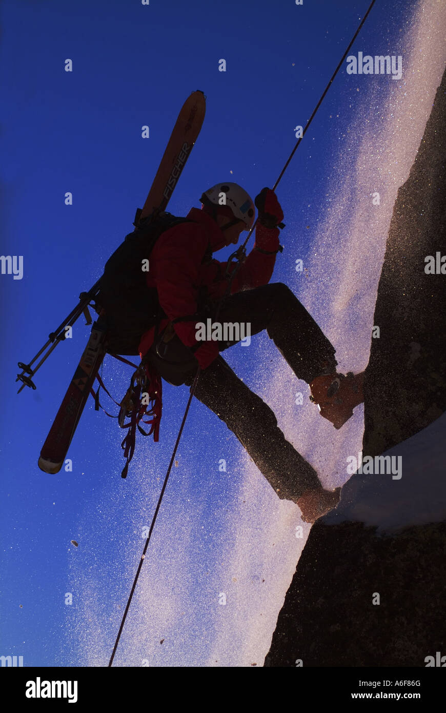 Man rappelling during small avalanche with skis on his back on Donner ...