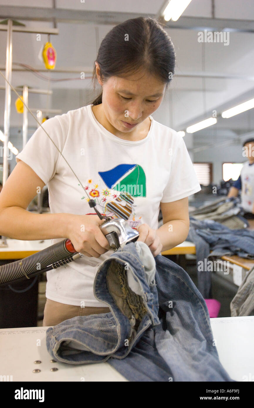 SHENZHEN GUANGDONG PROVINCE CHINA Woman worker trims loose threads off ...
