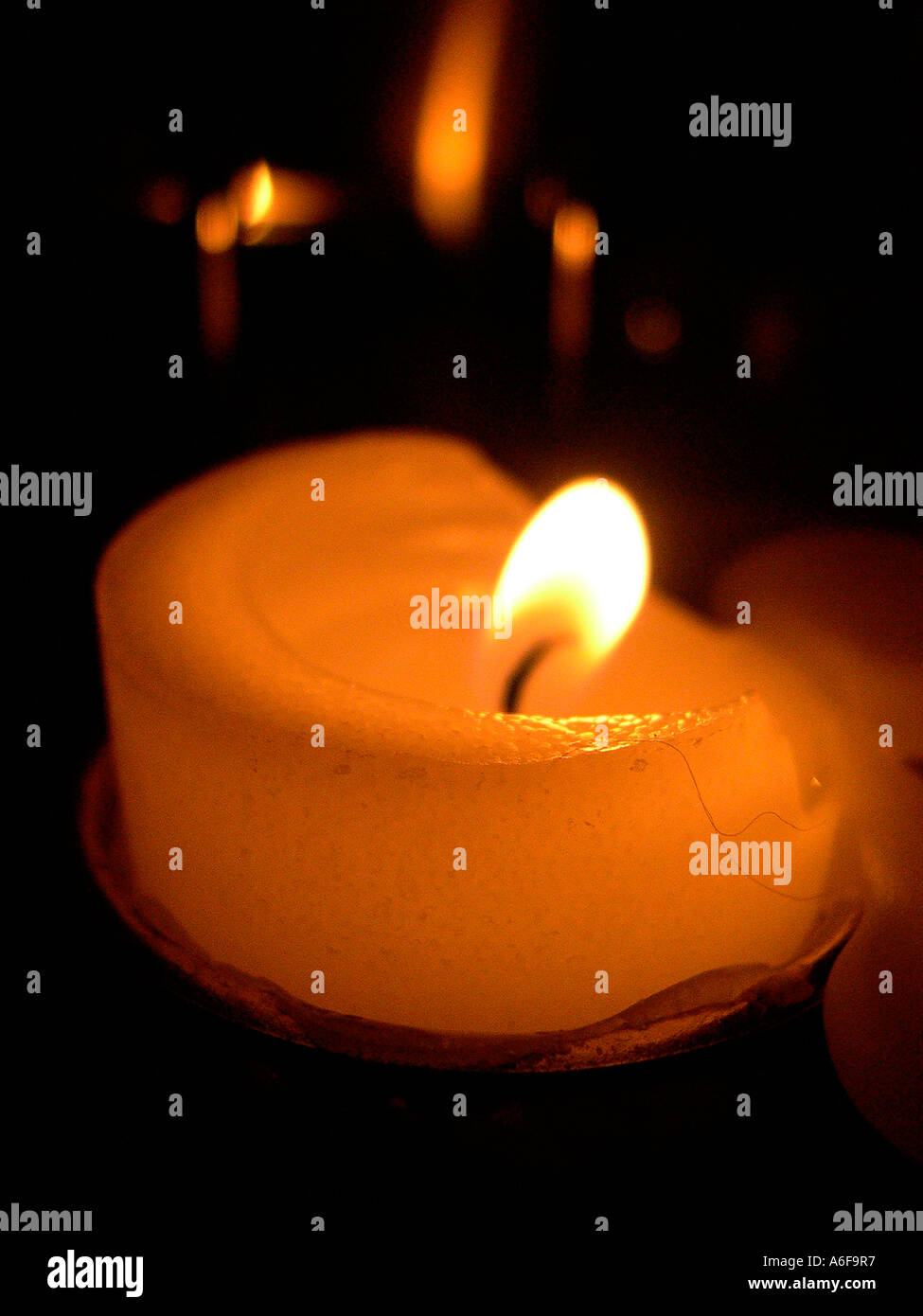 A SINGLE LIGHTED CANDLE CLOSE TO THE FIELD OF VISION OTHER LIGHTED ...