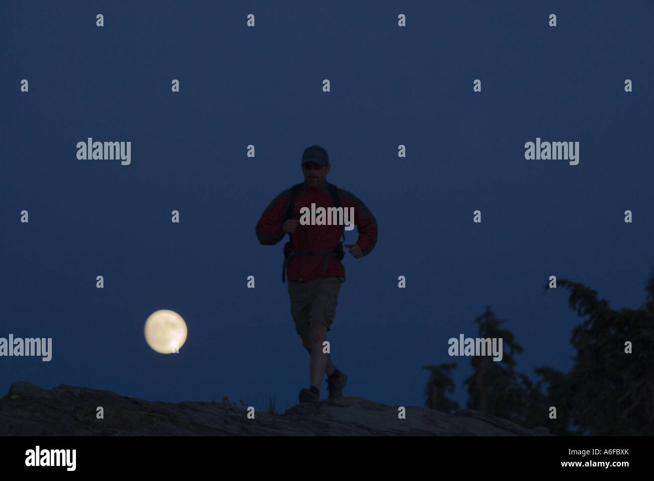 A man running and the full moon on the Tahoe Rim Trail above Lake Tahoe ...