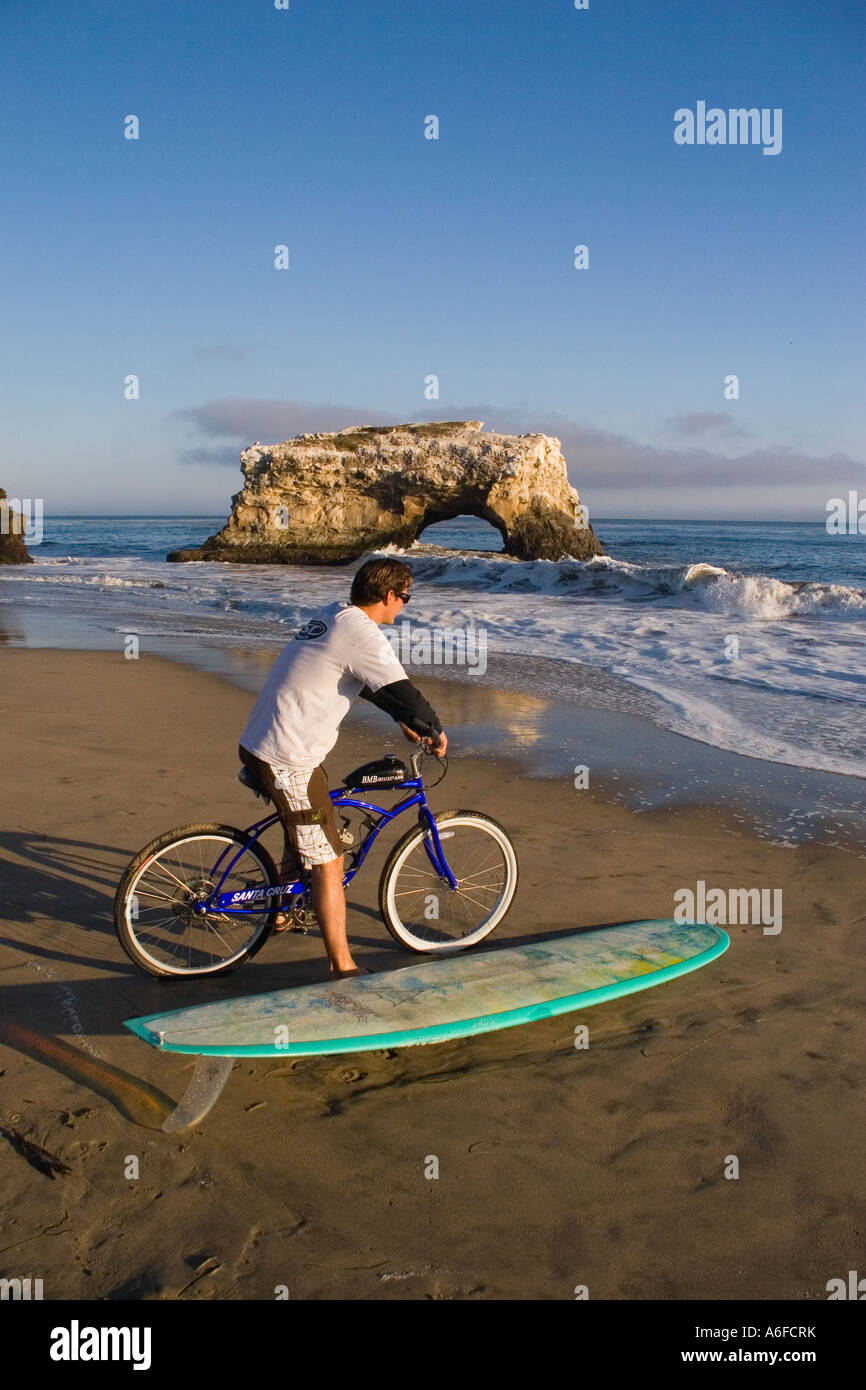 A Man with a bike and surfboard on the beach at sunset at Natural ...