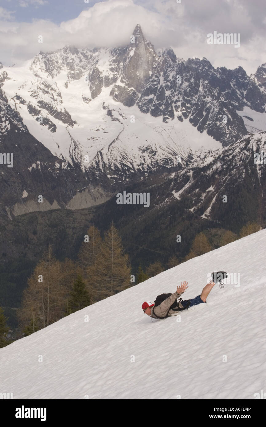 A man sliding on his stomach on snow in front of The Dru in Chamonix ...