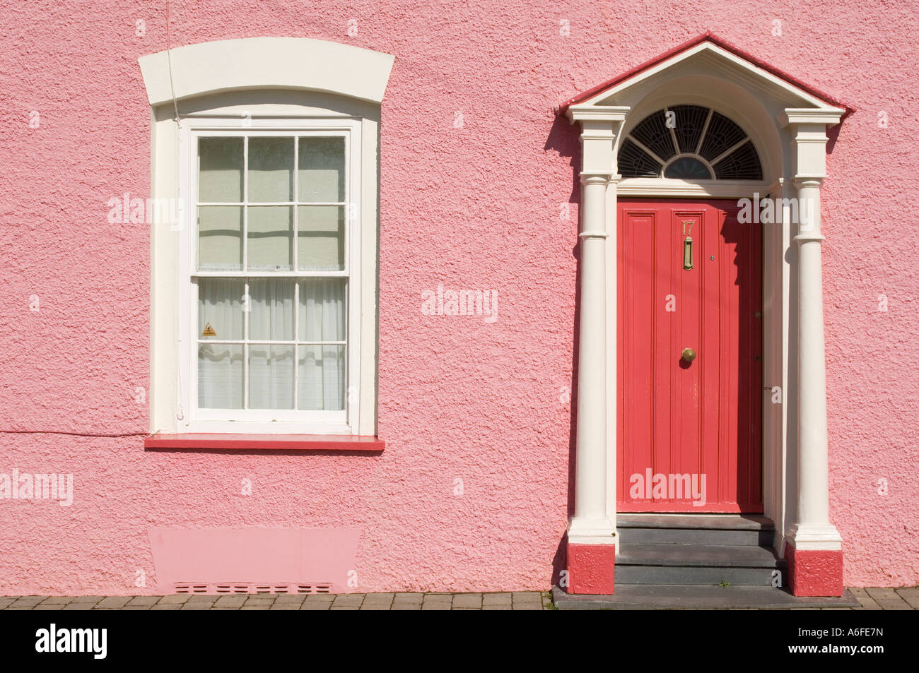 pink painted terraced house with columns and ornate doorway aberaeron ...