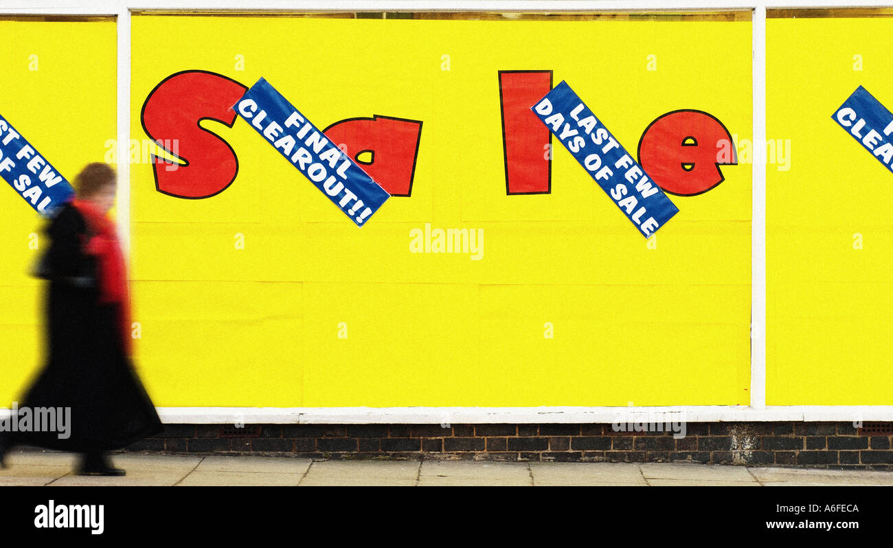 Woman walking past sale sign in shop window Stock Photo - Alamy