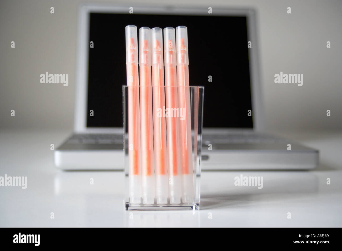orange pens with laptop computer Stock Photo - Alamy