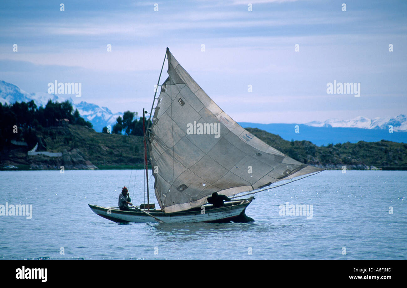 Traditional sailing boat on Lake Titicaca with snowy mountains behind ...