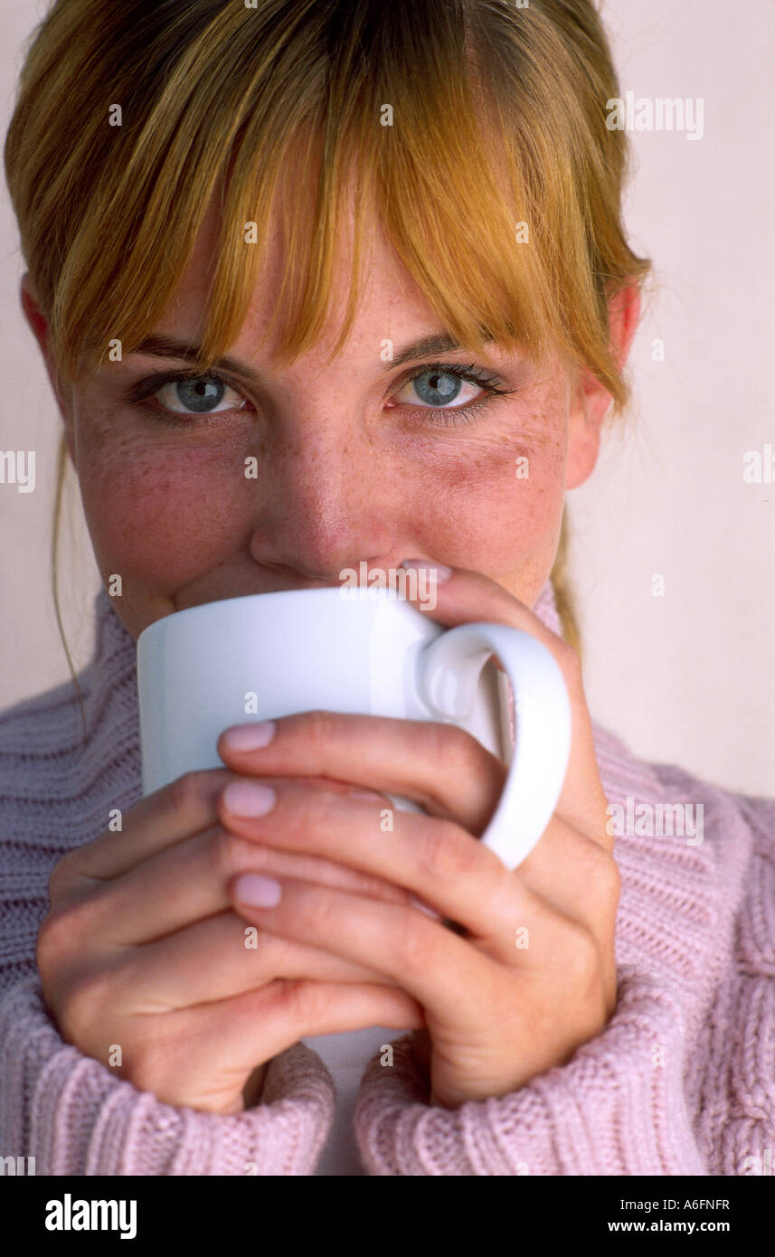 Woman sipping from a white mug Stock Photo - Alamy