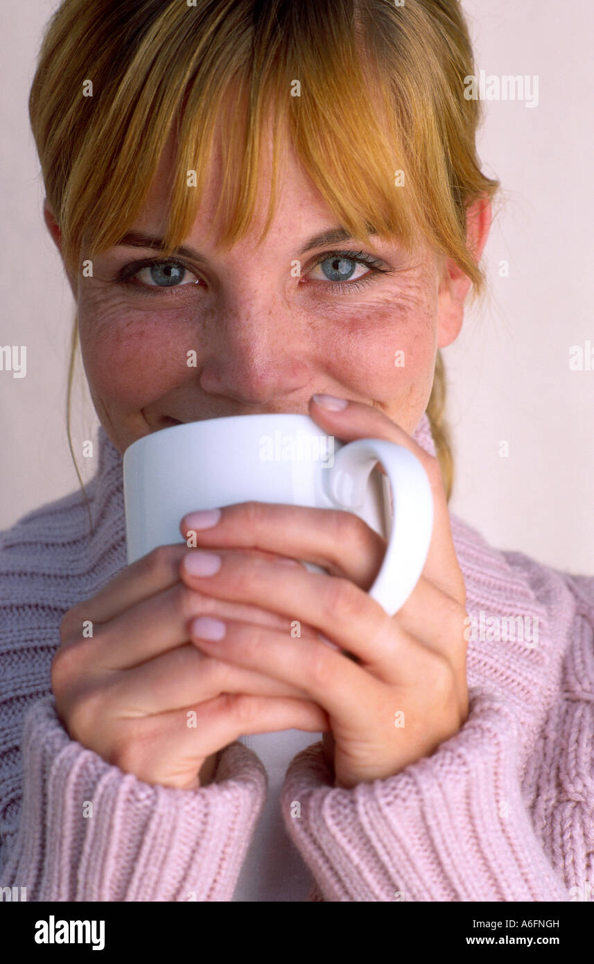 Woman sipping from a white mug Stock Photo - Alamy