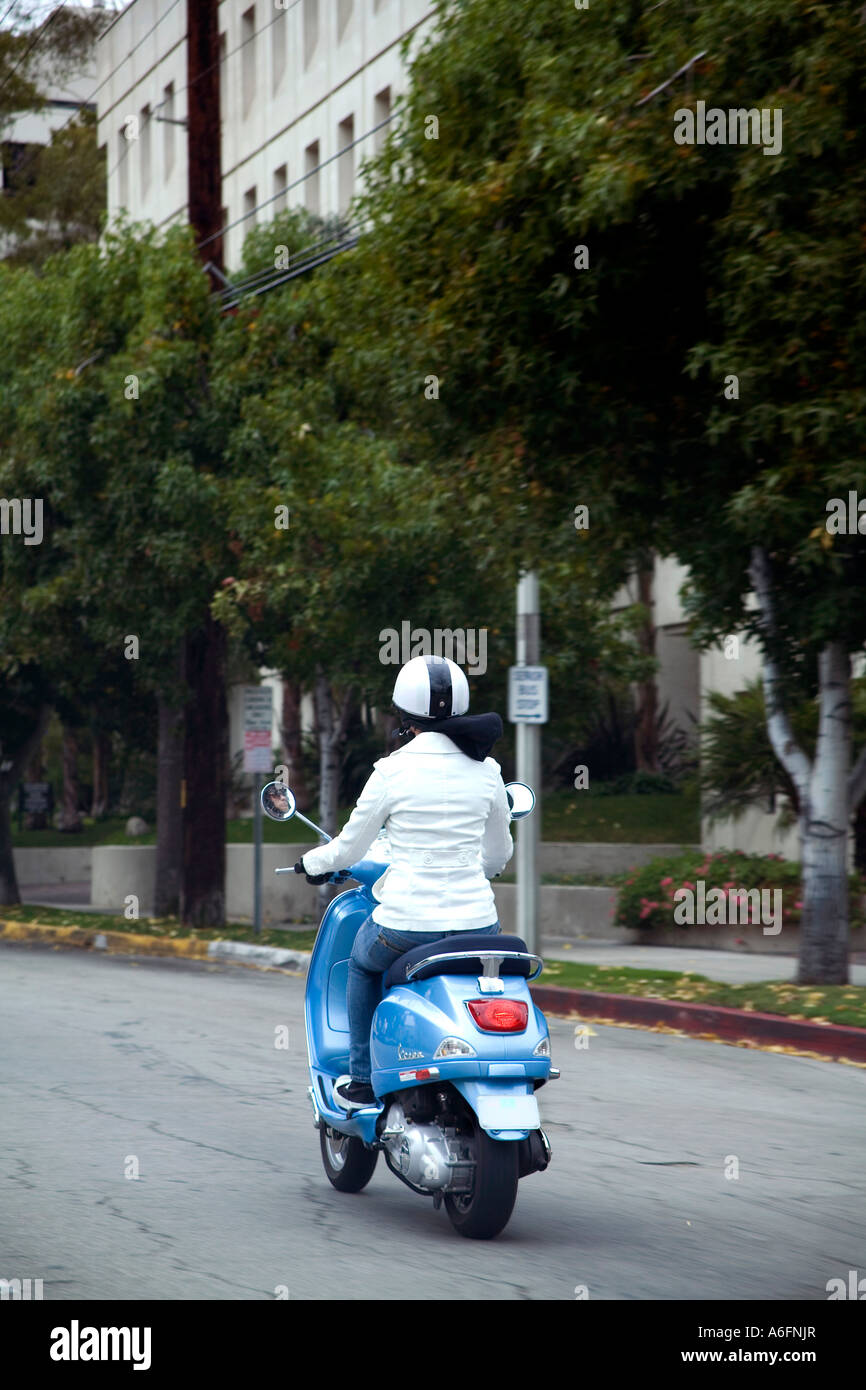Person riding a moped down the street Stock Photo - Alamy