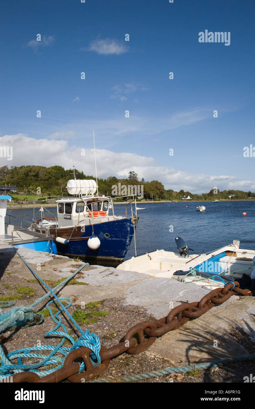 Rusty chain on pier with moored boats in harbour on Kenmare River ...