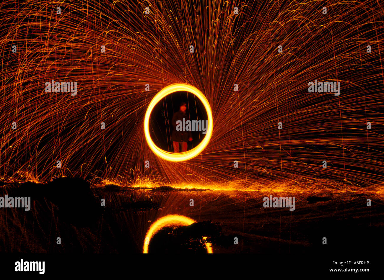 Man fire juggler juggling stream of flaming spinning burning fire in a ...