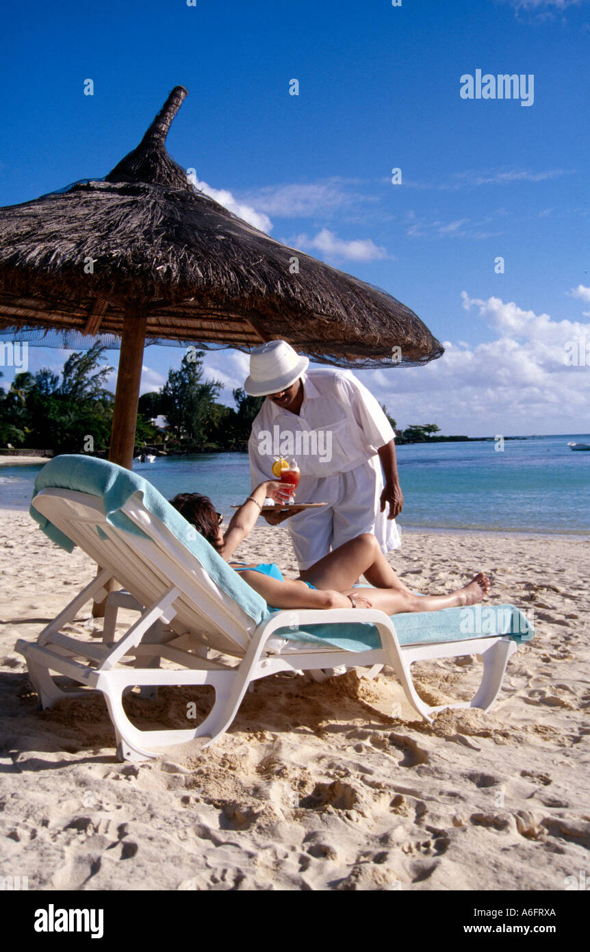 Waiter in white clothes serving a cocktail to a woman on a beach Royal ...