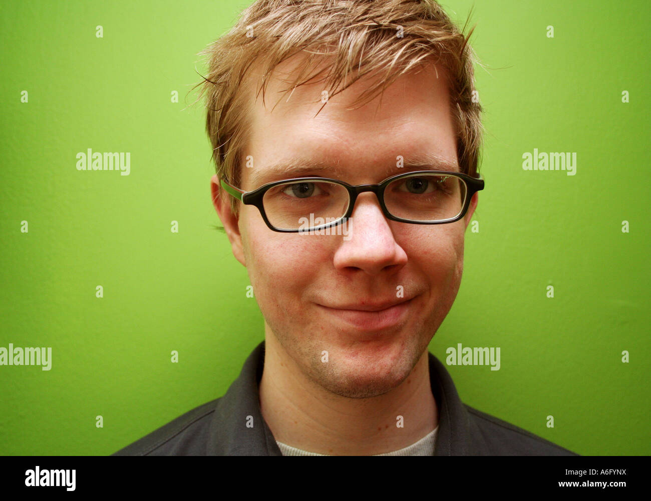 young man with glasses smiling green background Stock Photo - Alamy
