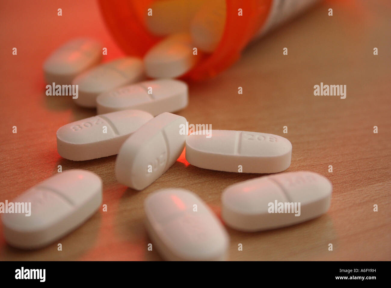 pills spilling from bottle onto wood background red backlight Stock ...