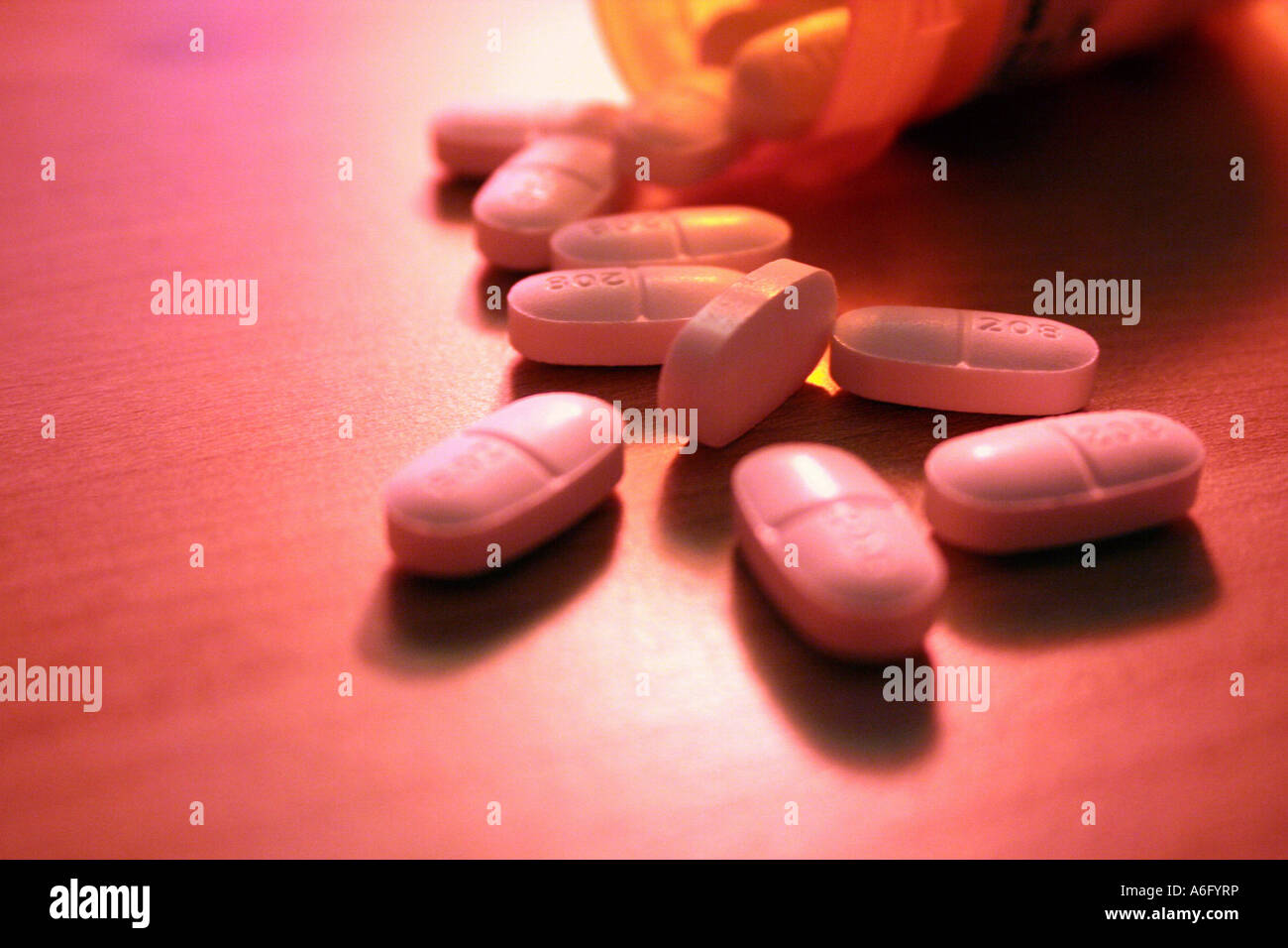 pills spilling from bottle onto wood background red backlight Stock ...