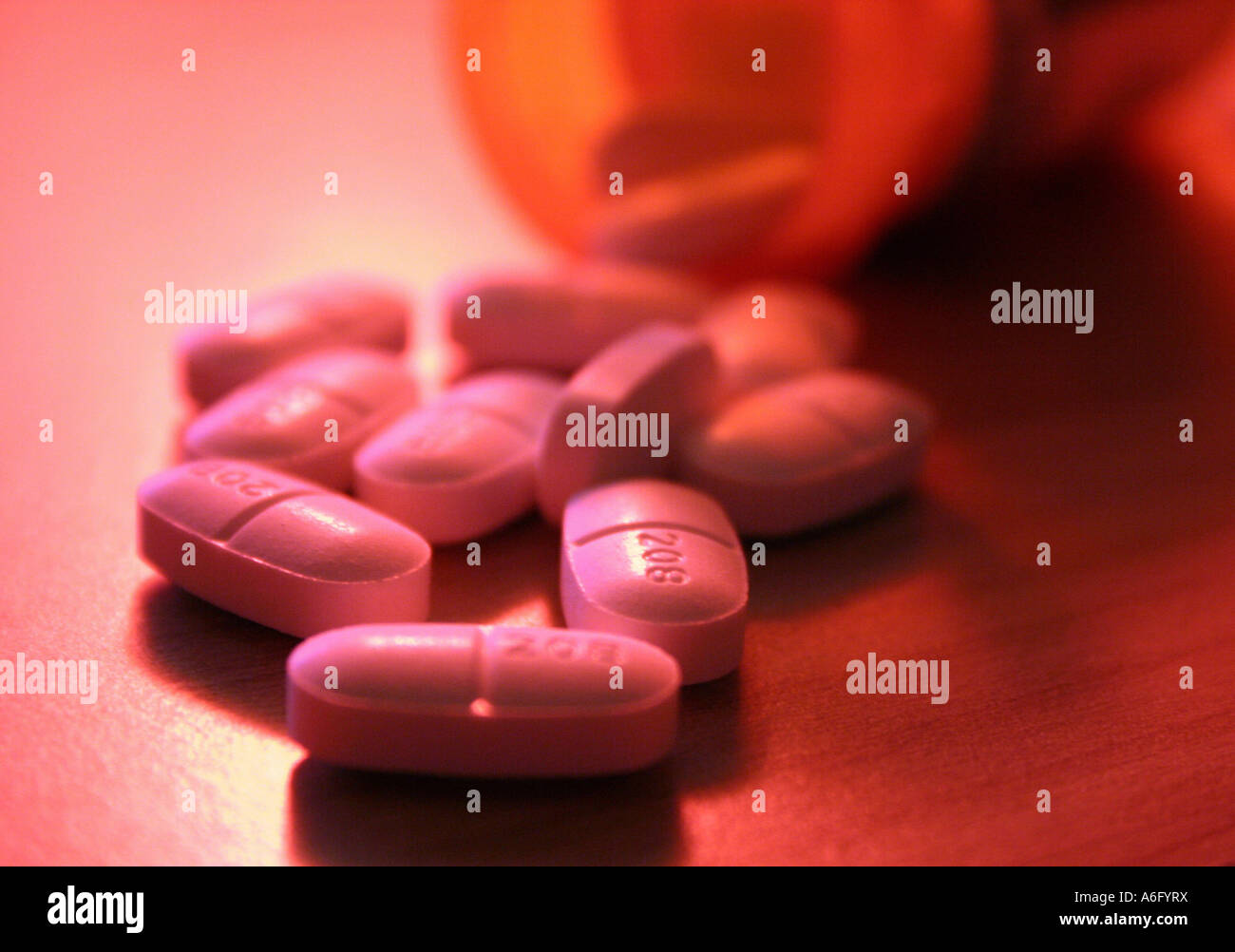 pills spilling from bottle onto wood background red backlight Stock ...