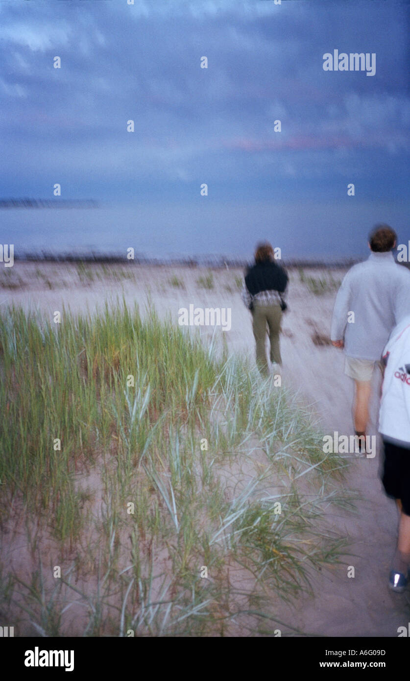 Blue night with men walking on the beach Stock Photo - Alamy