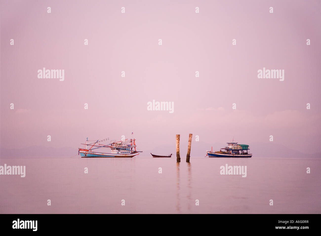 Two traditional boats moored offshore; Thai Fishing Boats at Dawn sunrise, as the sun rises over ...
