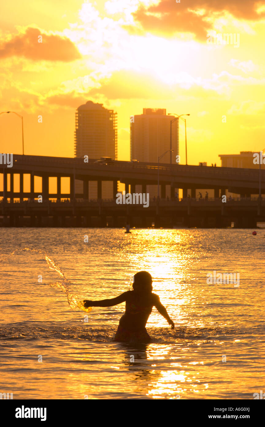 MIAMI FLORIDA USA Swimmers play in shallow water as sun sets over ...