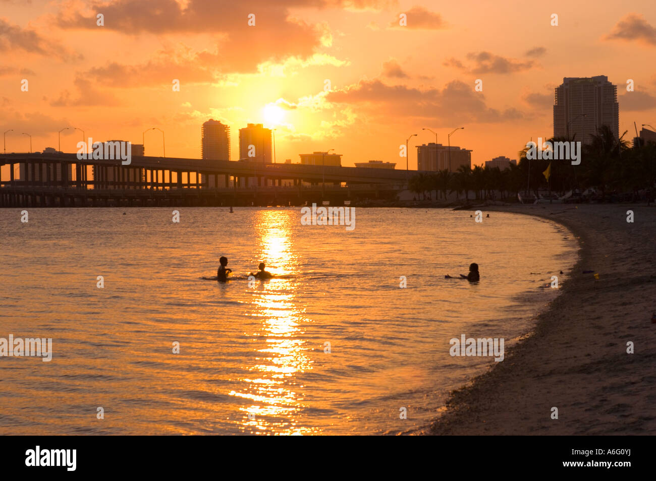 MIAMI FLORIDA USA Swimmers play in shallow water as sun sets over ...