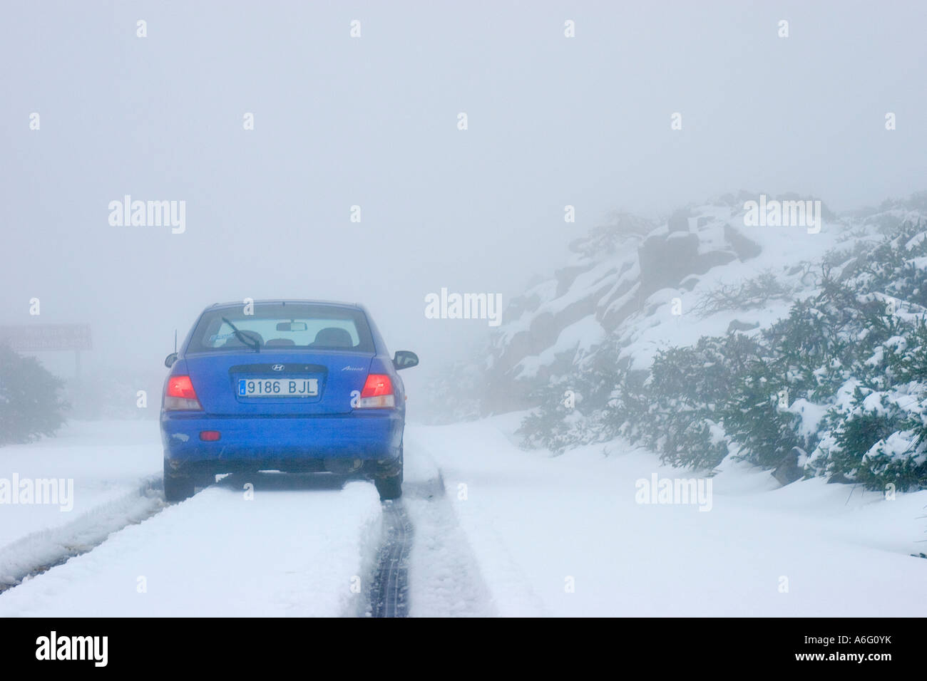 blue car rear view driving through snow fog on Mount Roque de los ...