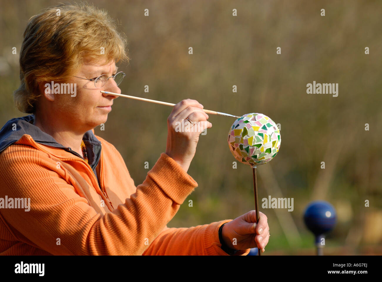 Woman glazing a ball pasted up with ceramic tiles Stock Photo - Alamy