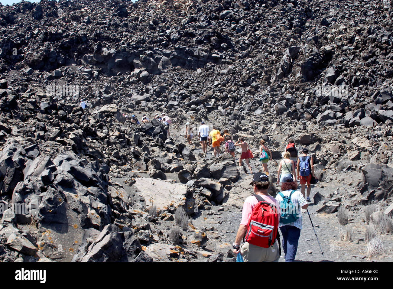 People tourists and visitors walking up Nea Kameni volcanic volcano ...