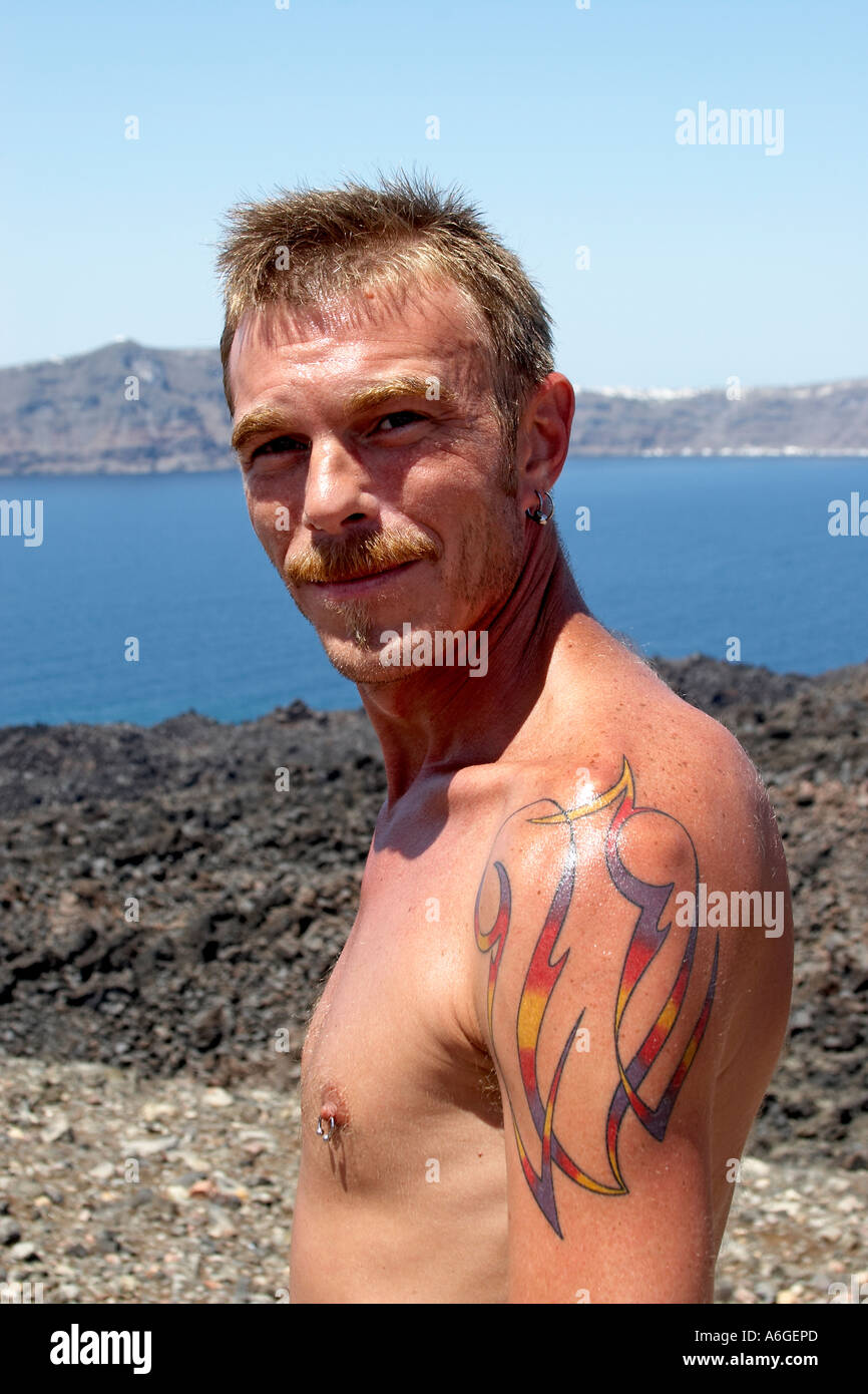 American man with tattooes on his arm on Nea Kameni volcanic volcano ...