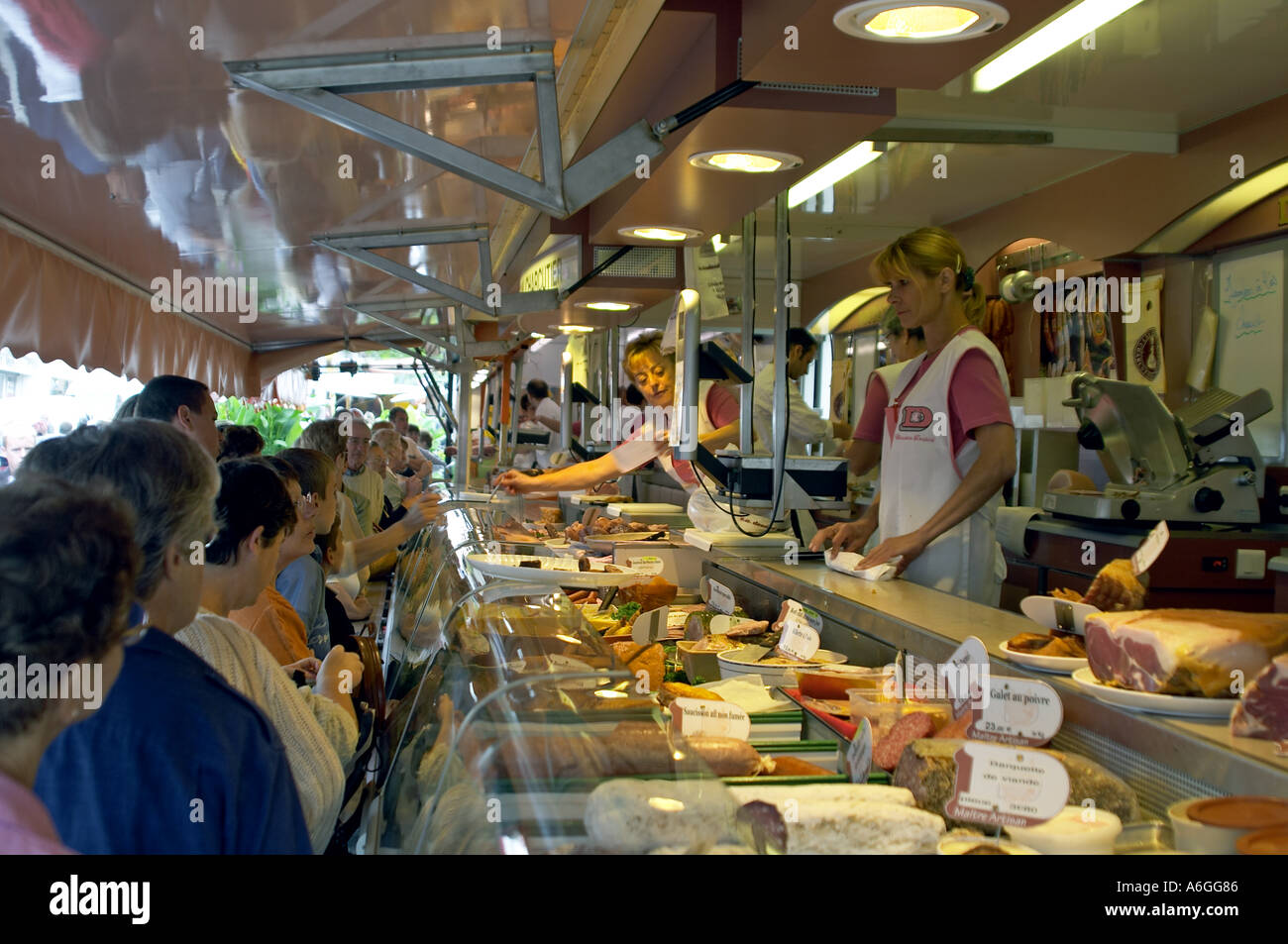 People shopping at French market cheese and cold meats stall in L Aigle ...