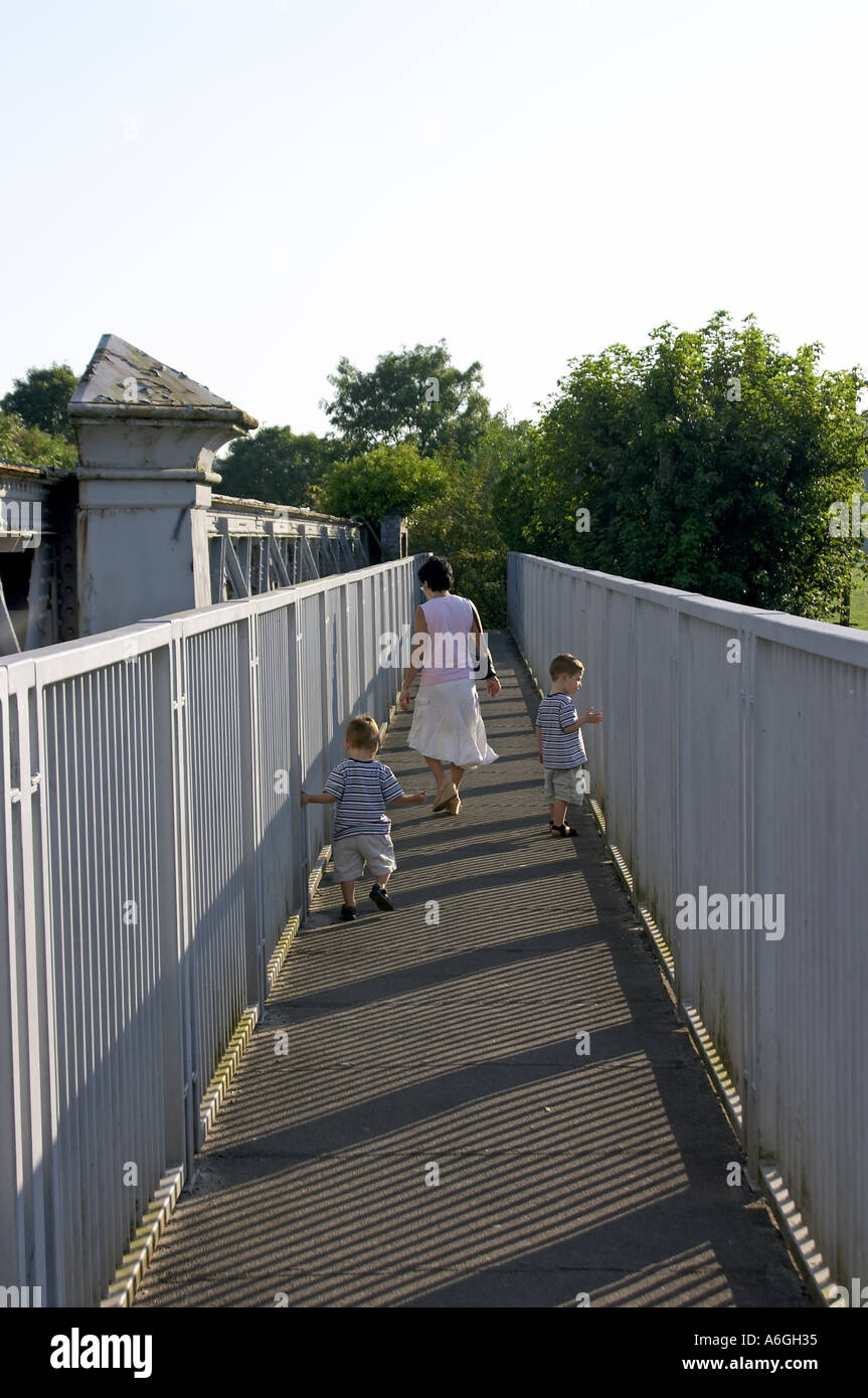 Mother and two boys walking along a bridge Stock Photo - Alamy
