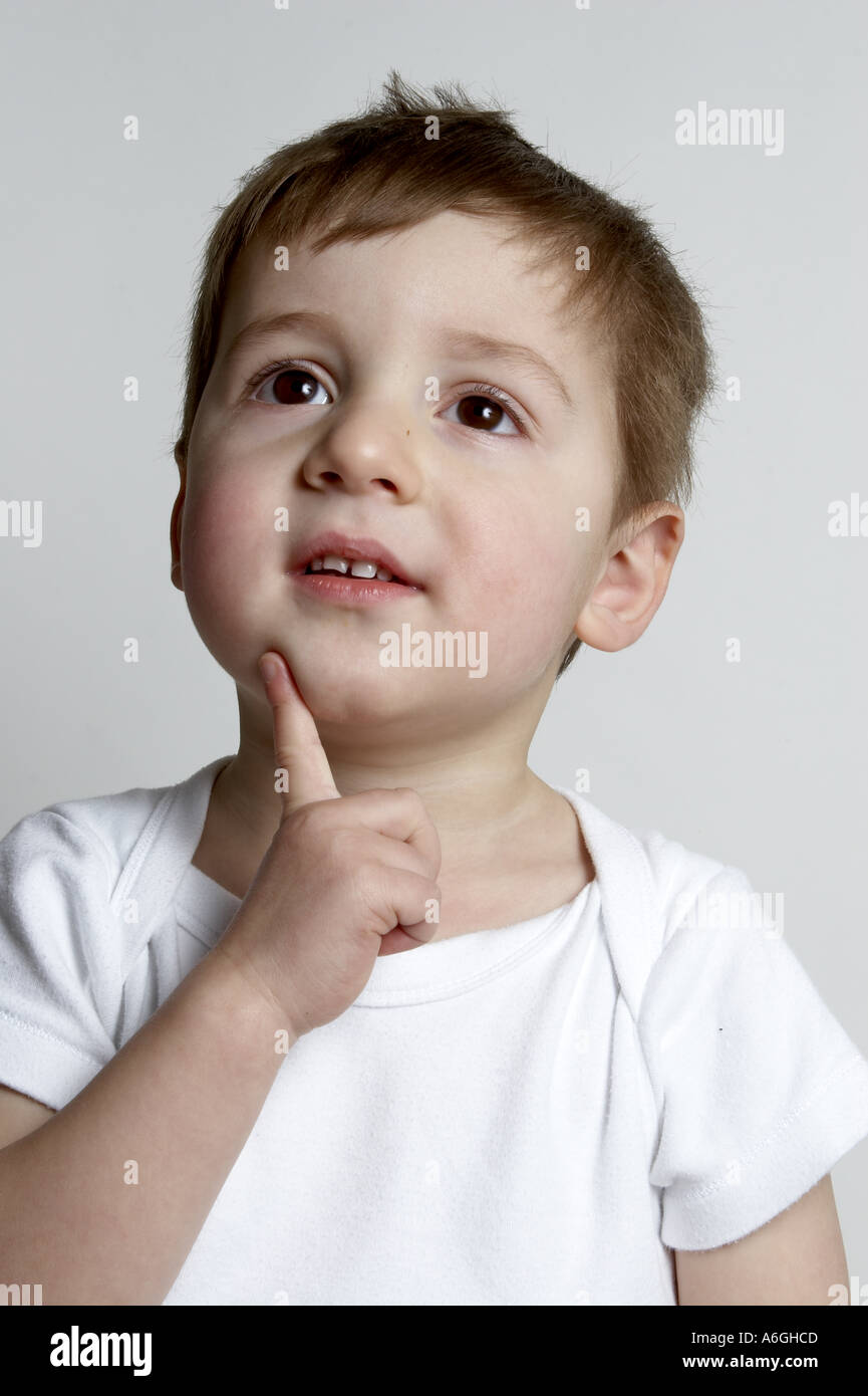 Young boy wondering and questioning with finger to his chin Stock Photo ...