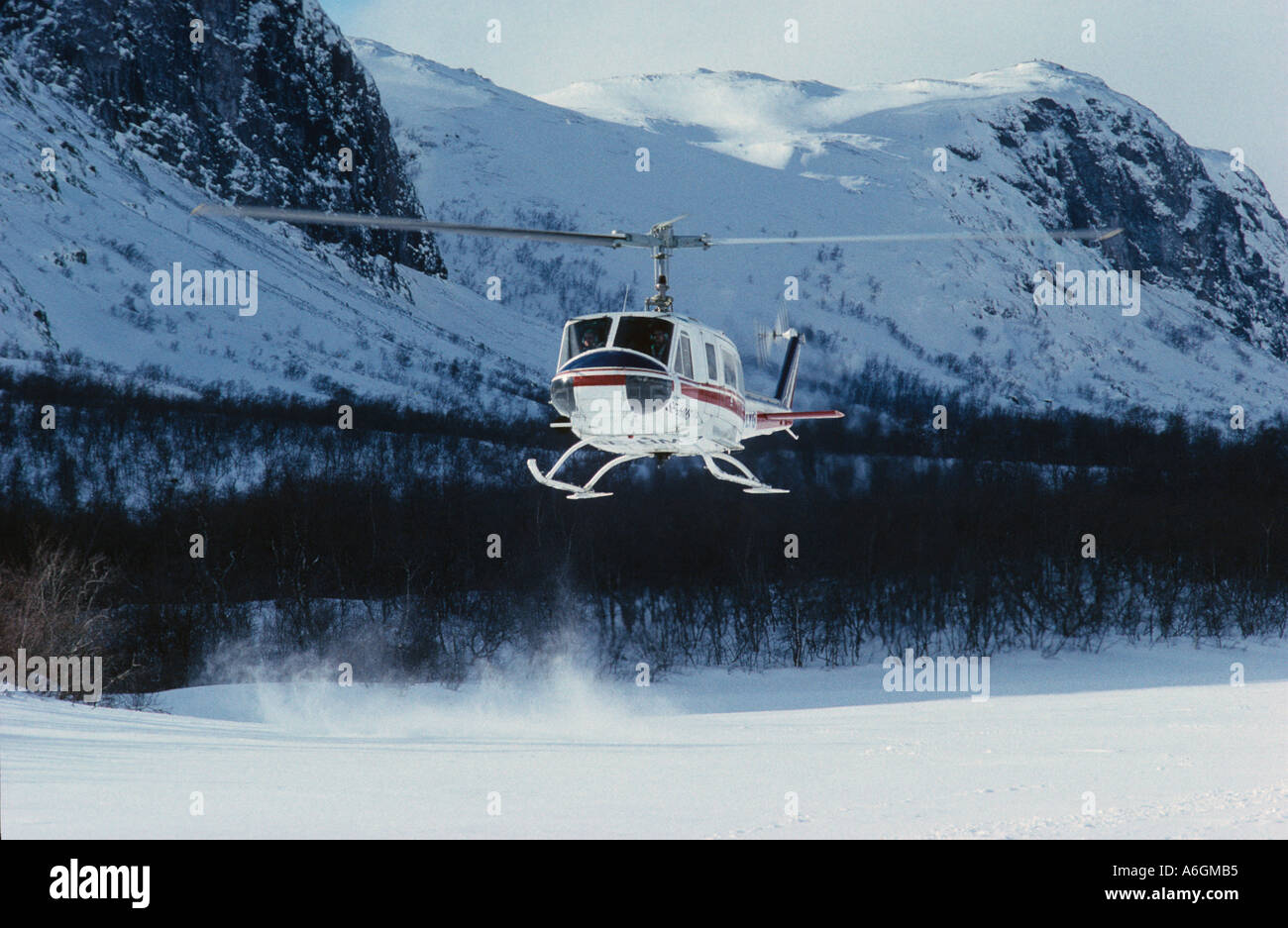 A Bell Jetranger helicopter comes in to land on a frozen lake near ...