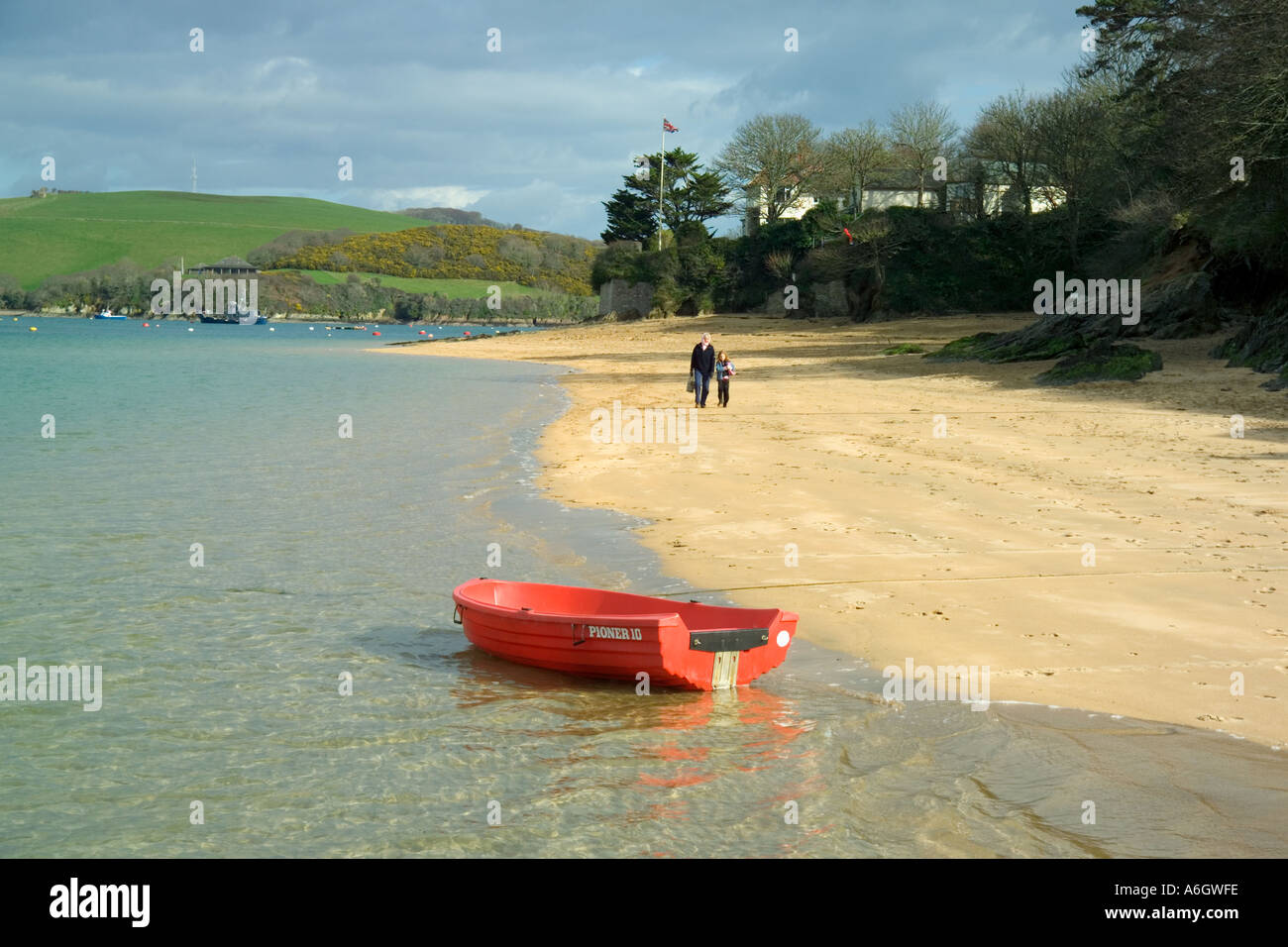 Salcombe South Devon UK red boat in shallow water two people walking ...