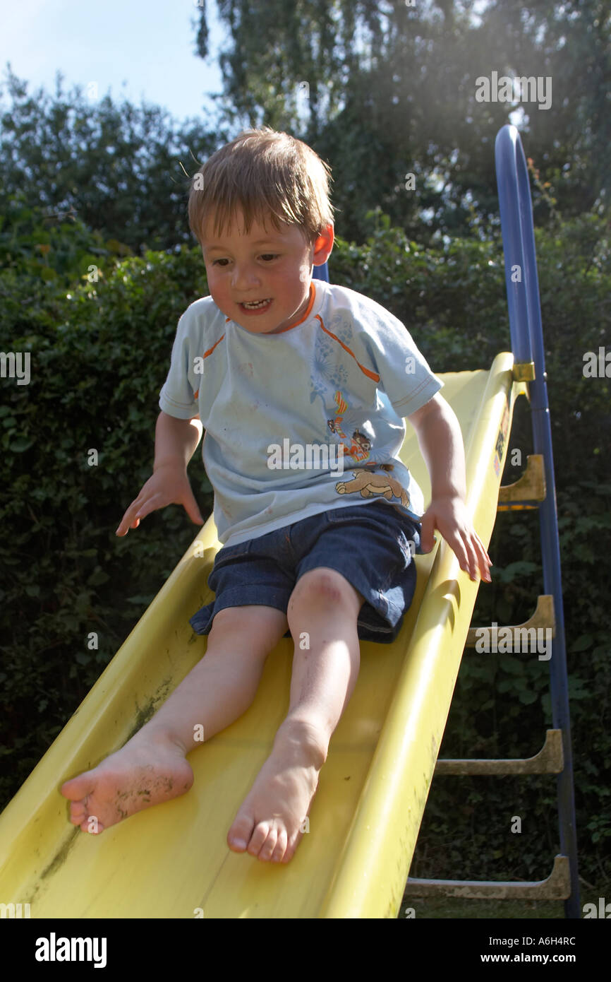 Young boy child coming down a yellow slide CJWH Stock Photo - Alamy
