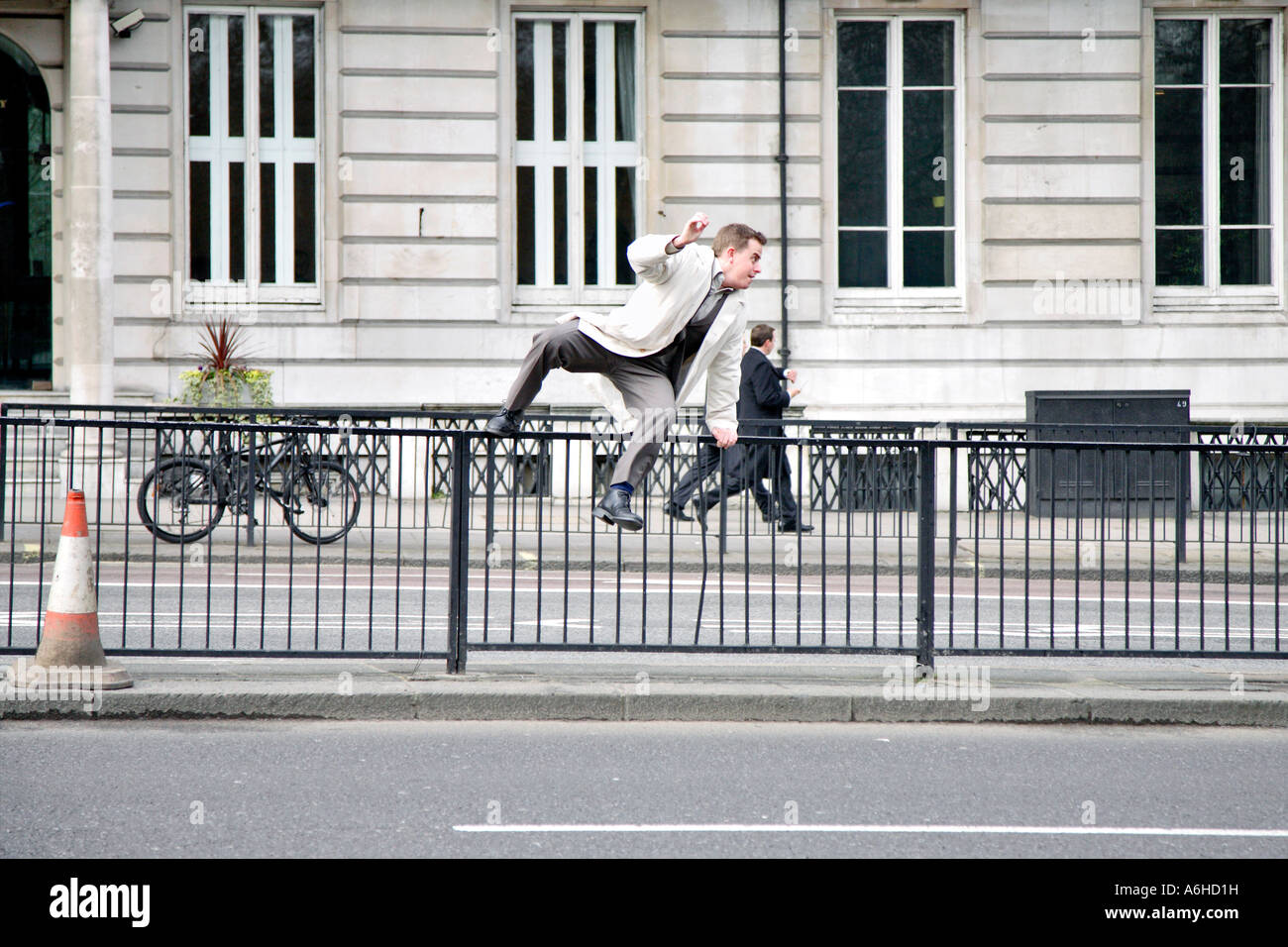 A man jumps a fence across a busy road in London Stock Photo - Alamy