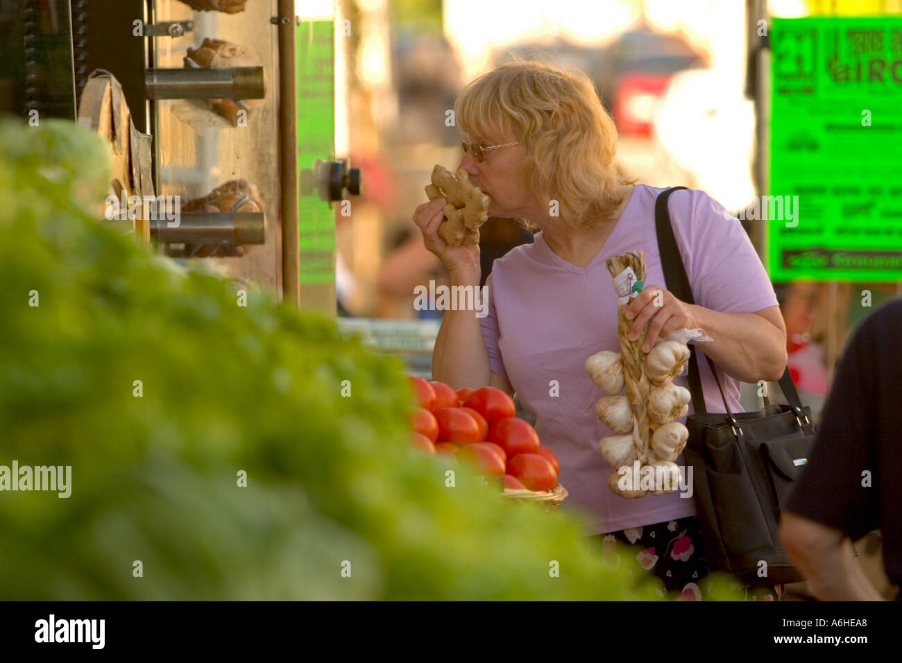 Woman smelling garlic while holding garlic string at french market ...