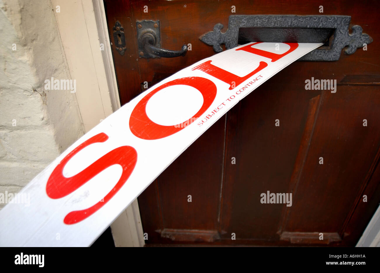 a sold sign hanging out of a house letterbox Stock Photo - Alamy