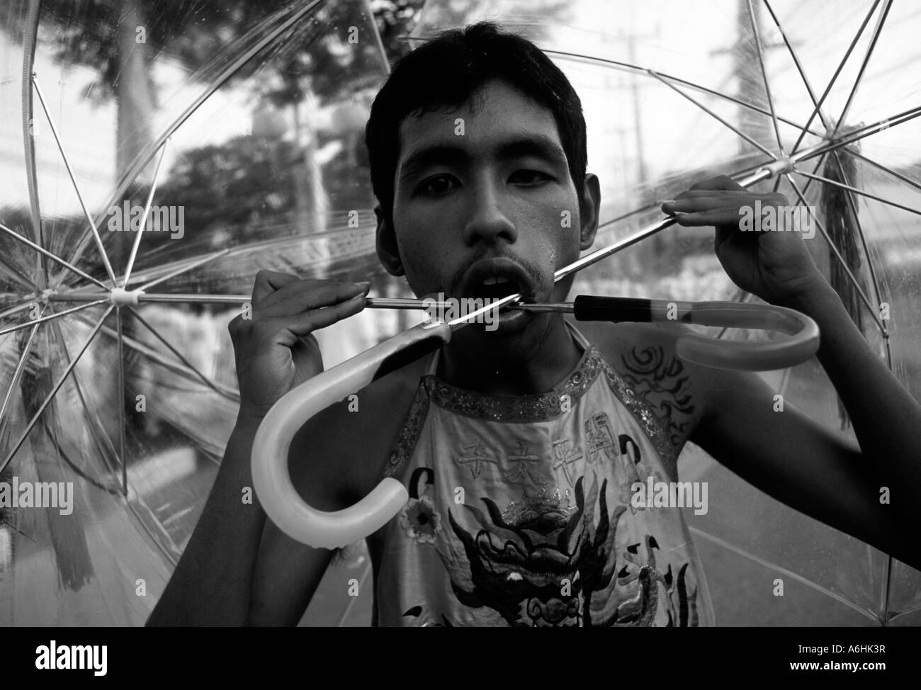 Man with 2 umbrellas through his face.vegetarian festival Thailand ...