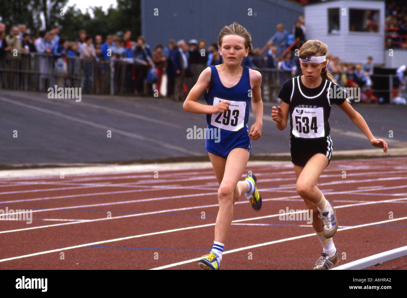 Two young girls competing in a track event at a tartan track stadium ...