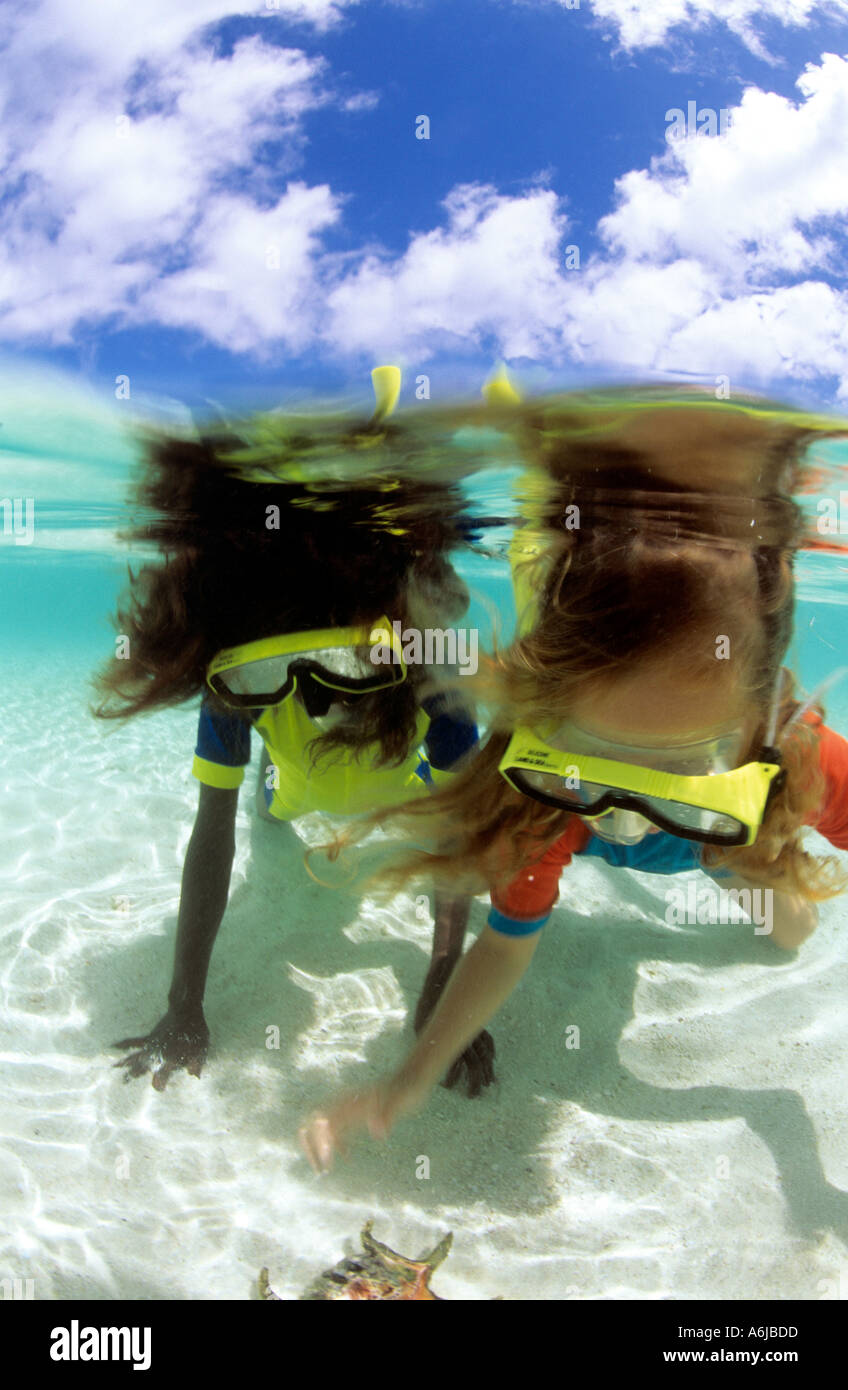 Underwater split view of Two girls snorkeling above white sand in the ...