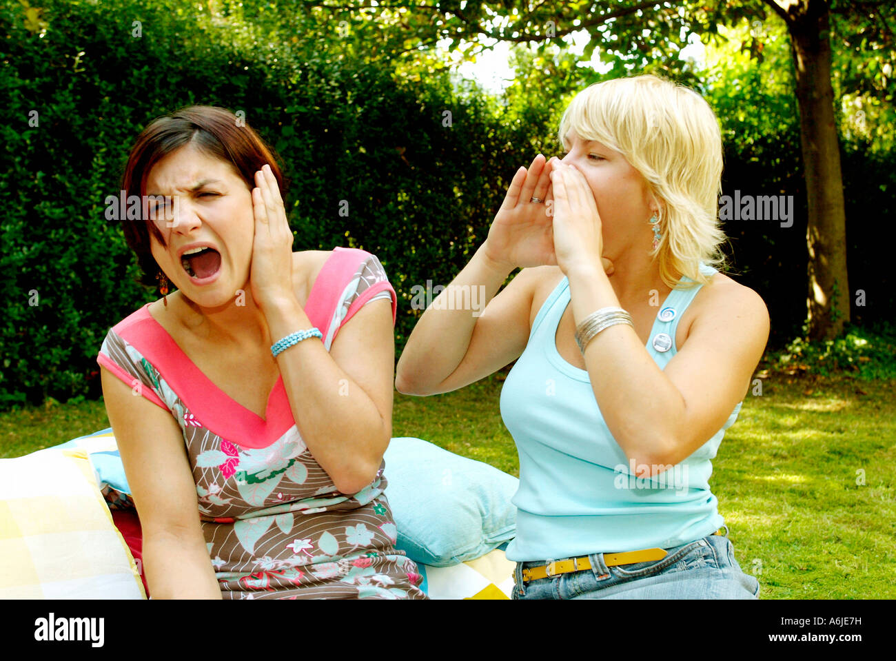 Young women in a garden, one of them shouting Stock Photo - Alamy