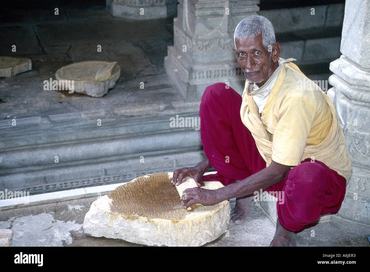 man is producing paste from sandelwood in the Chaumukh Jain Temple ...