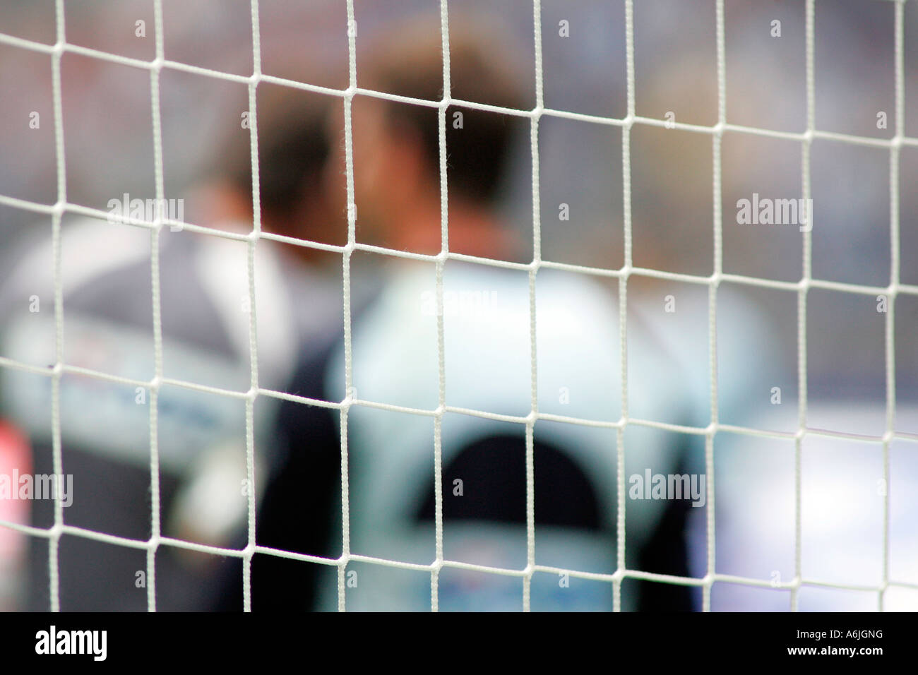 Football players seen through a goal net Stock Photo - Alamy