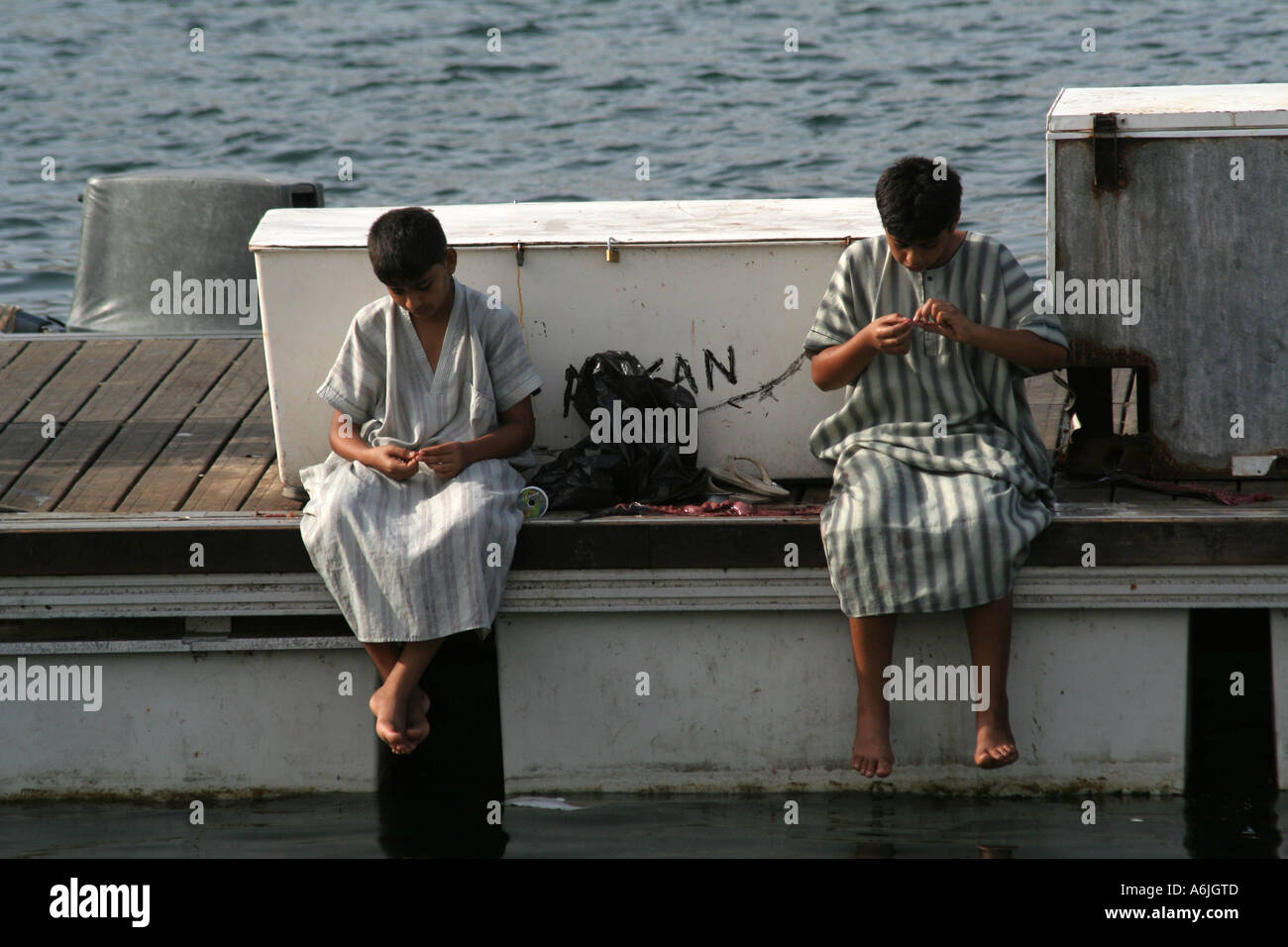 Muscat, Oman, boys bait their lines, fishing from a dock Stock Photo ...