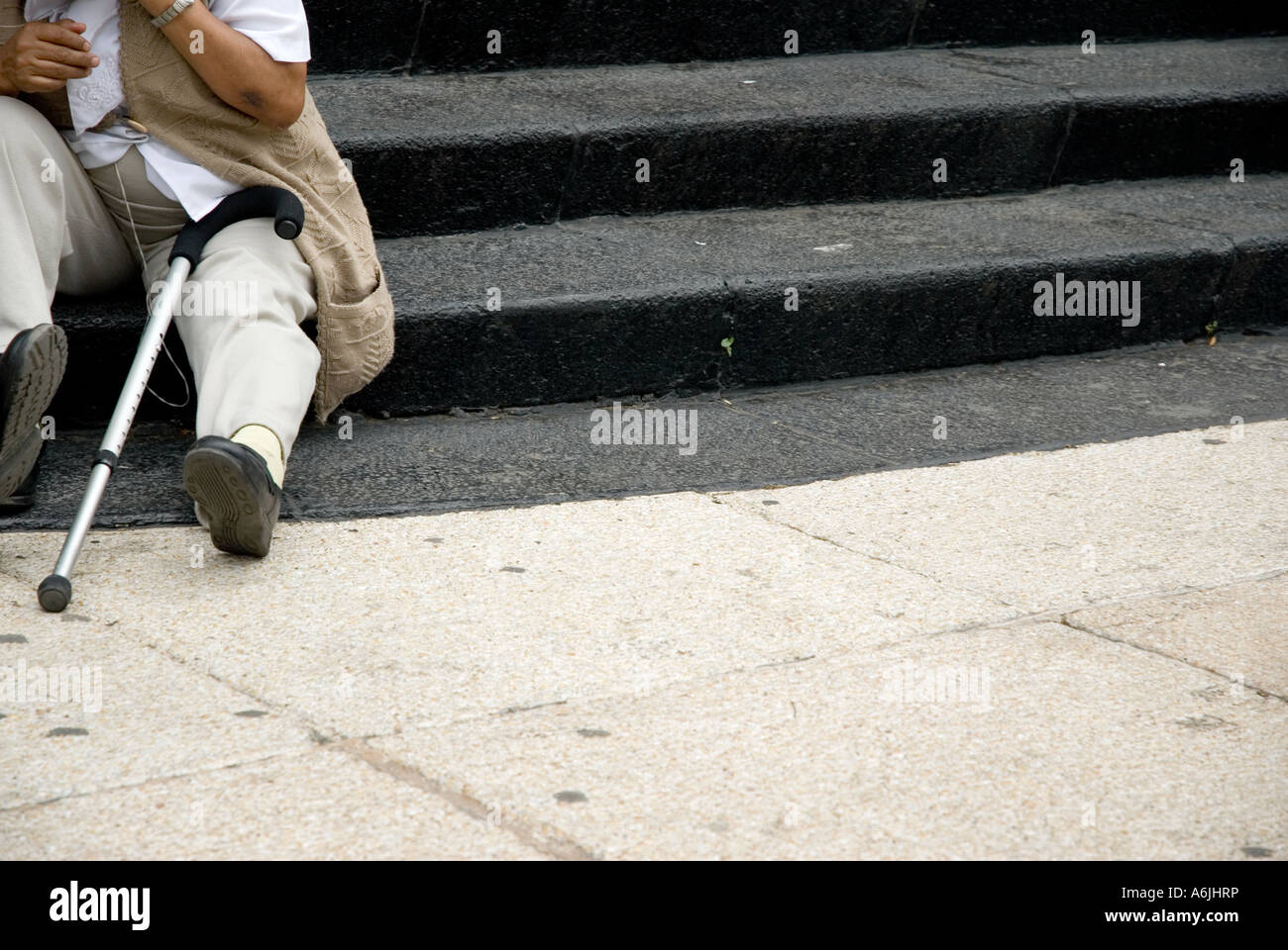 disabled person with a walking stick seated on the step - mexico city ...